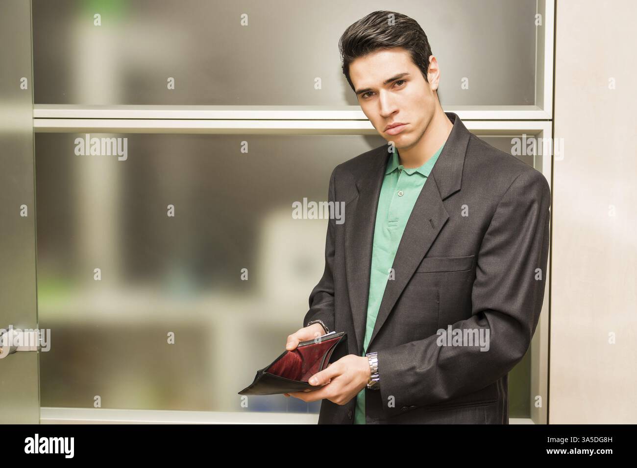 Sad looking young business man in office showing empty wallet Stock ...