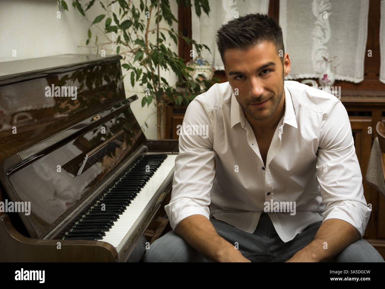 Young handsome male artist smiling while sitting next to his wooden ...