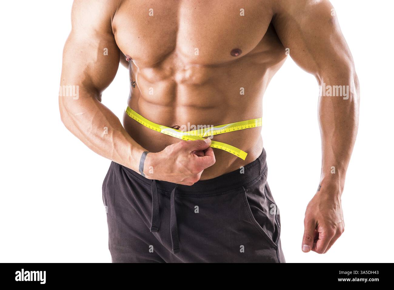 Muscular bodybuilder man measuring belly and hips with tape measure ...