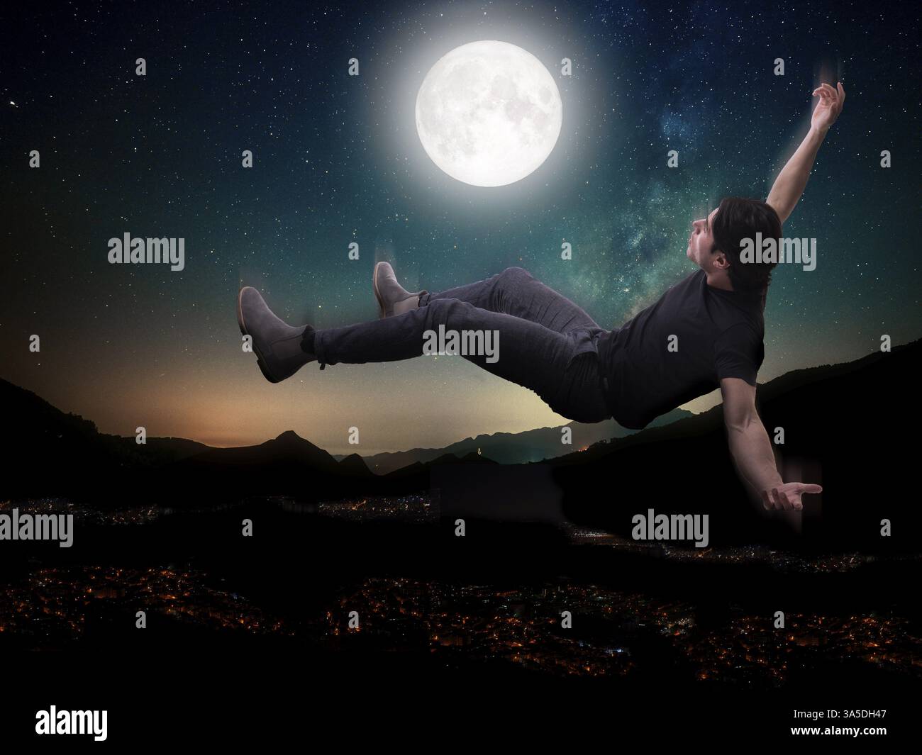 Casual young man falling down above dark city light in mountains with ...