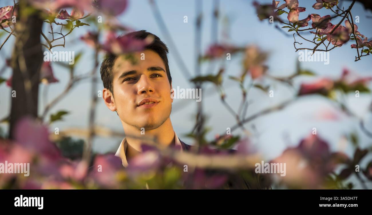 Good looking male model at couuntryside, among flowers, enjoying nature ...