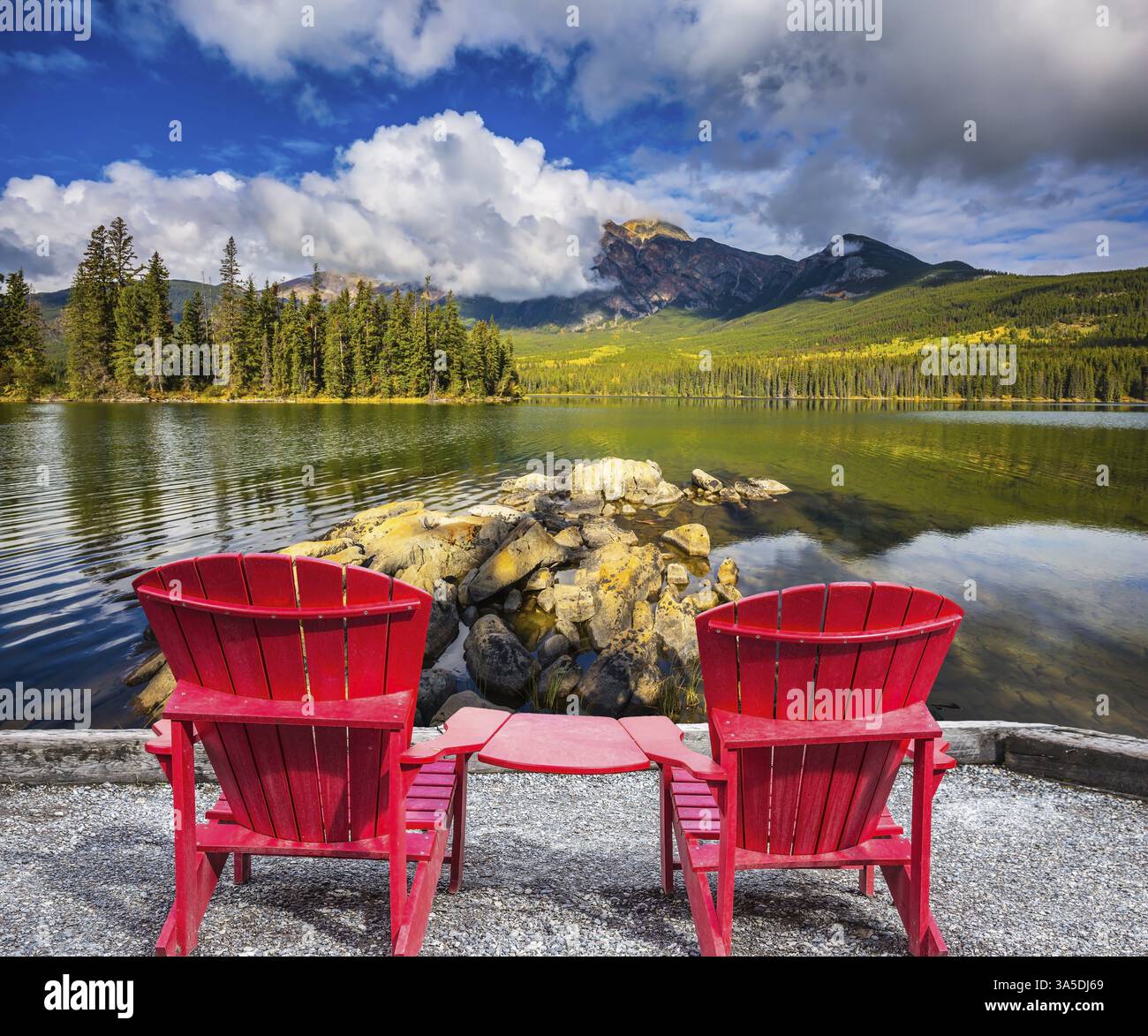 Pyramid Mountain reflected in Pyramid Lake. Two red chaise lounges for ...