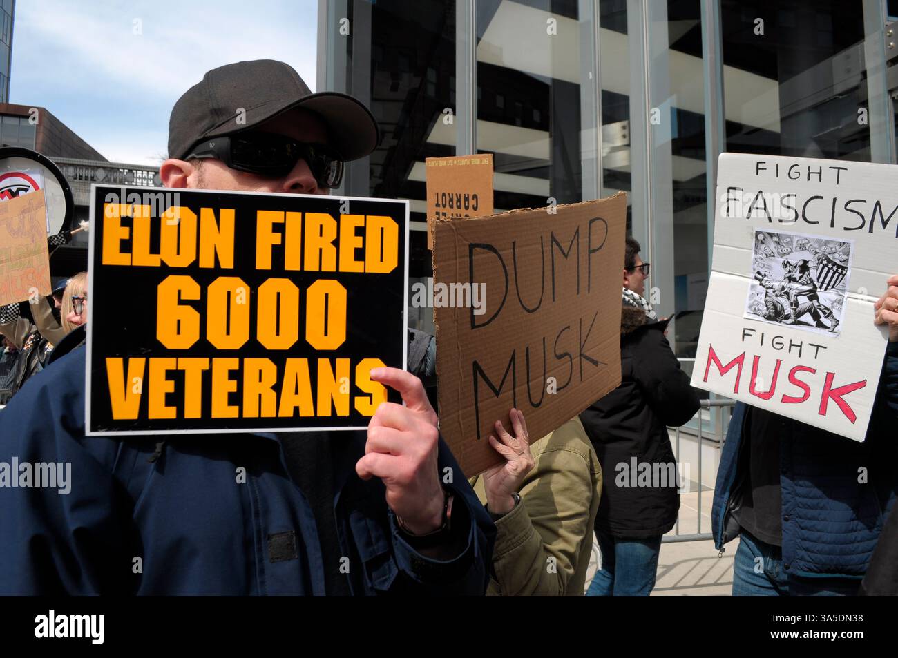 Anti-Elon Musk demonstrators hold placards outside of a Tesla showroom ...