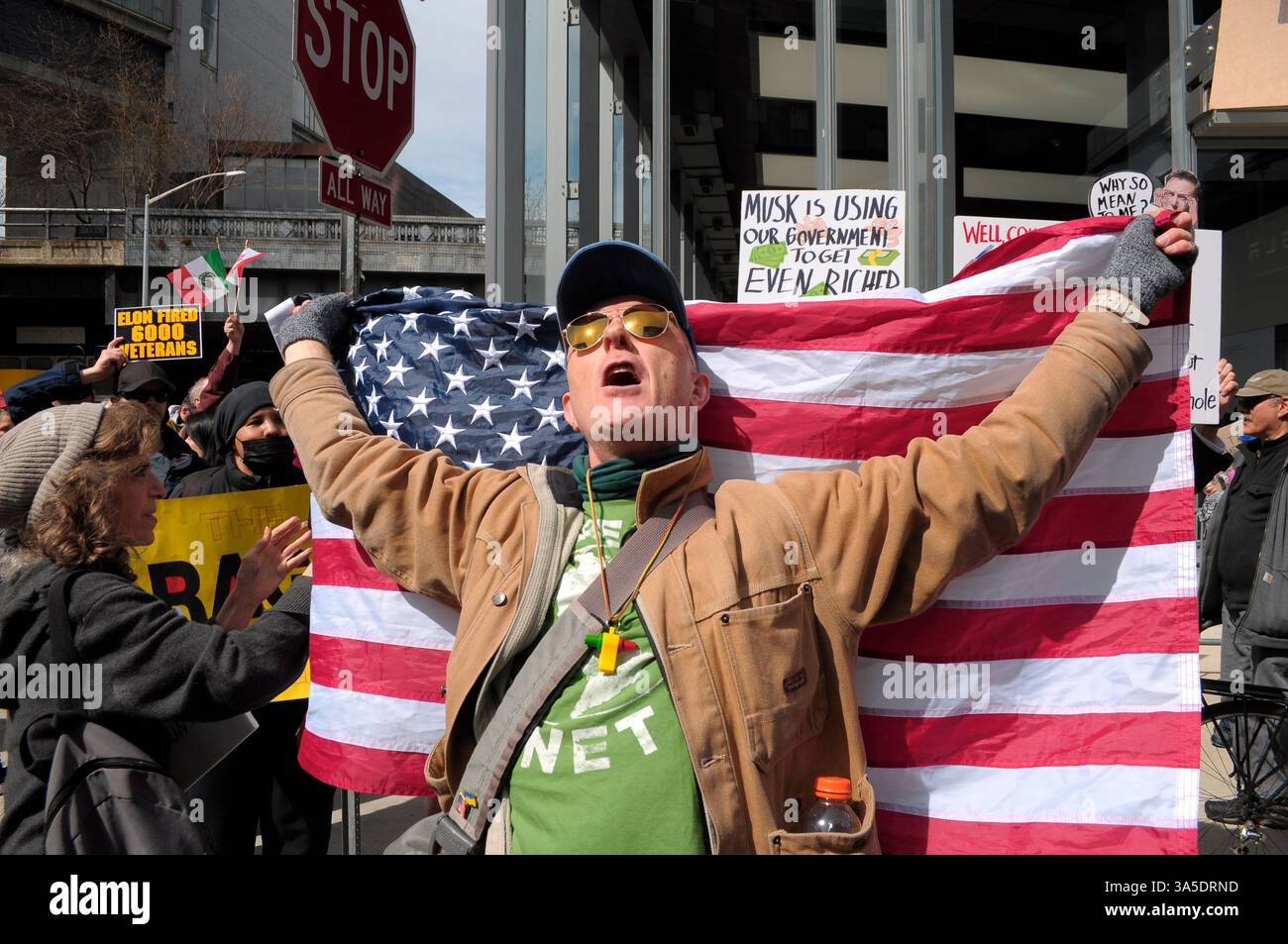An anti-Elon Musk demonstrator holding the American flag chants slogans ...