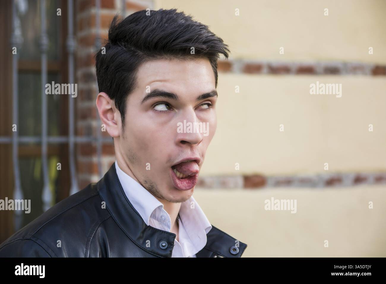Young man outdoor doing silly face and stupid expression, looking to a ...