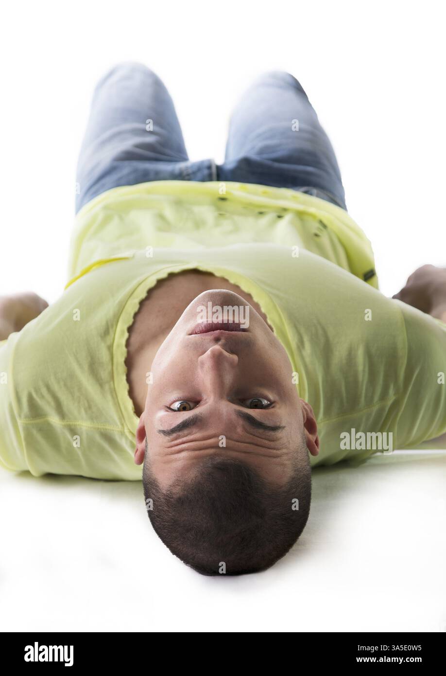 Handsome young man laying on the floor, belly up, looking at camera ...