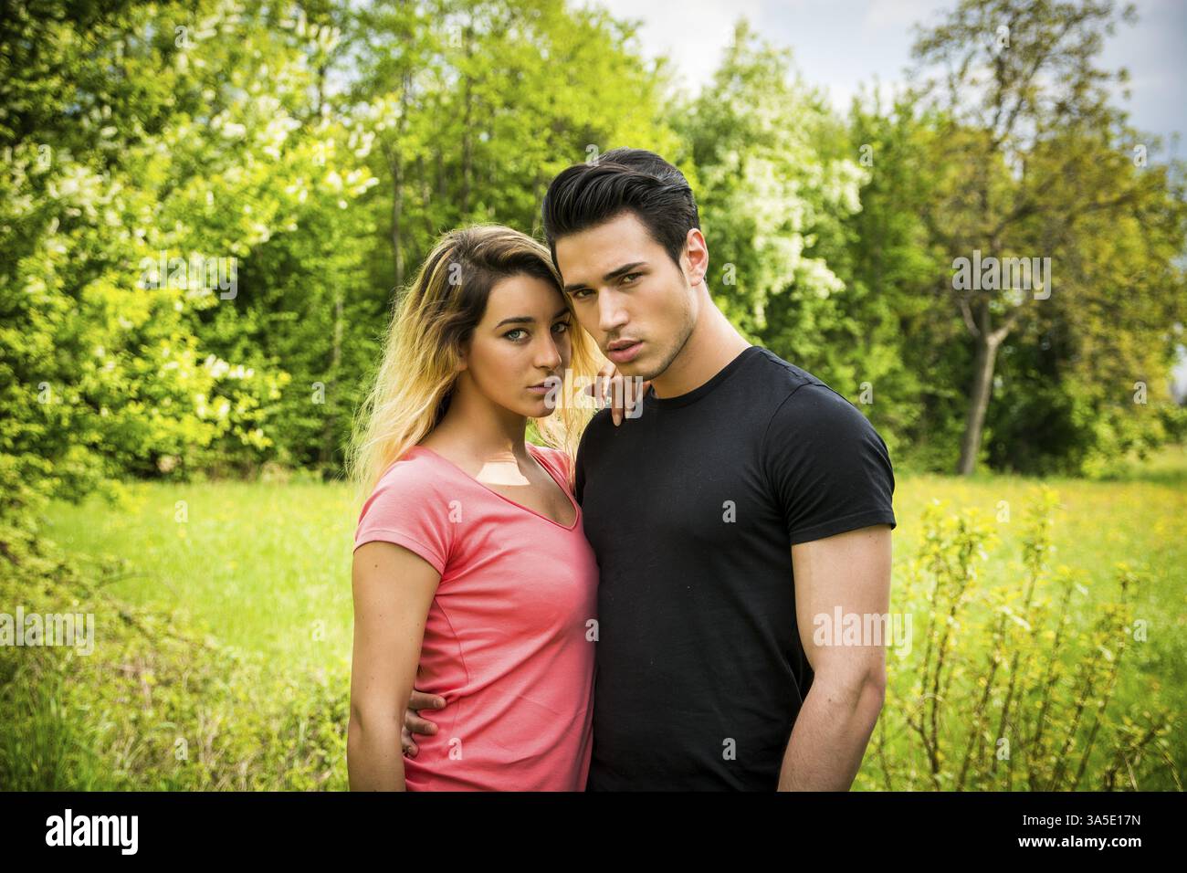 Boyfriend and girlfriend standing in countryside in green luscious ...