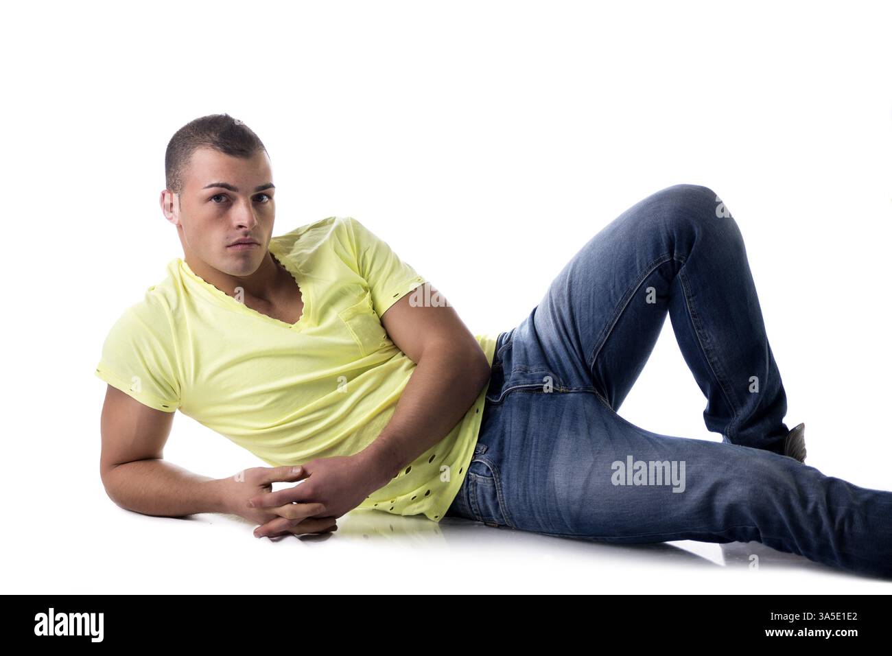 Handsome, muscular young man laying on the floor, resting on his elbow ...