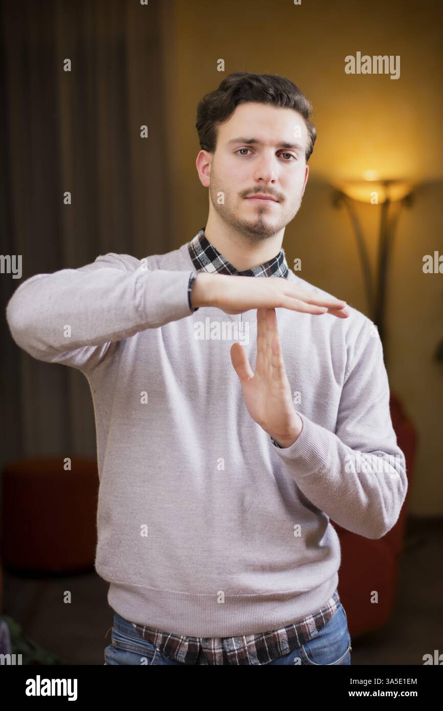 Attractive young man doing time-out sign, indoor shot inside a house Stock Photo - Alamy