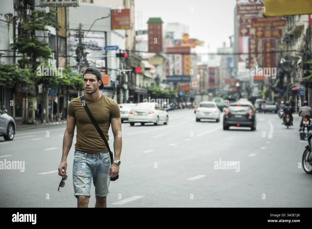 Muscular young handsome man walking on busy sunny street in Bangkok ...