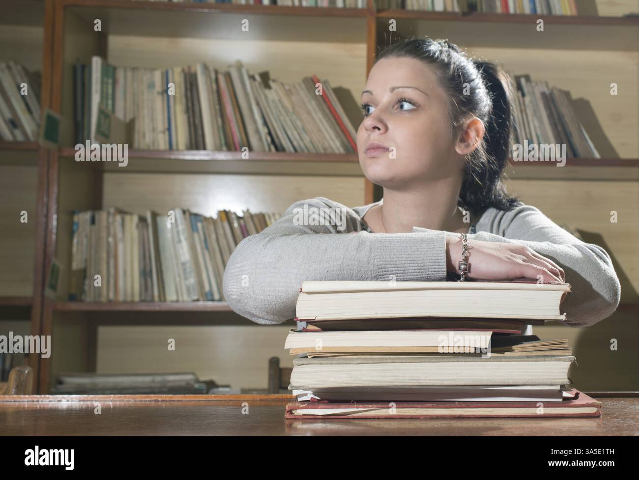 Student girl in a library. Looking at book Stock Photo - Alamy