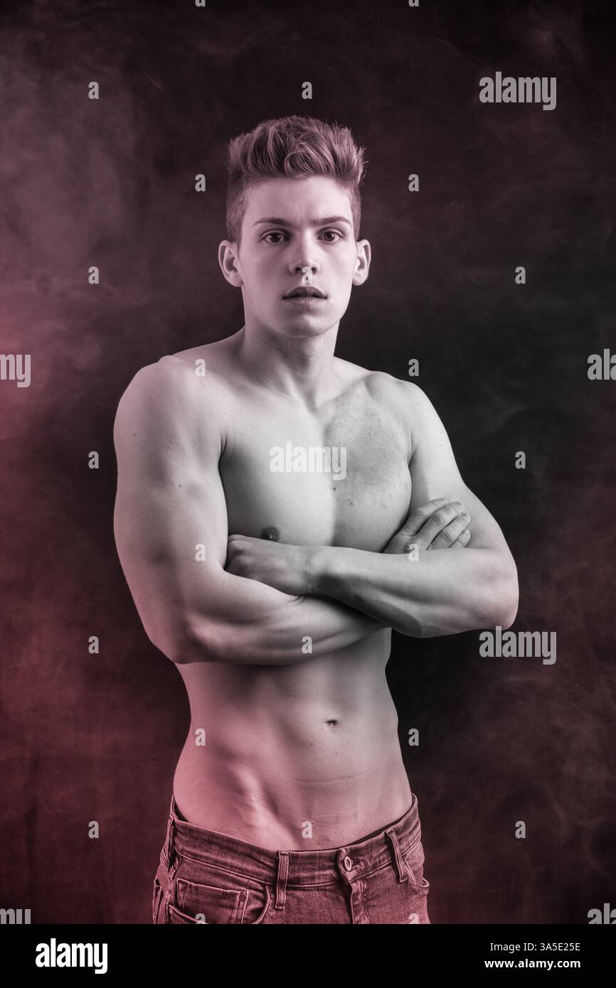 Handsome bodybuilder in relaxed pose, looking at camera on dark ...