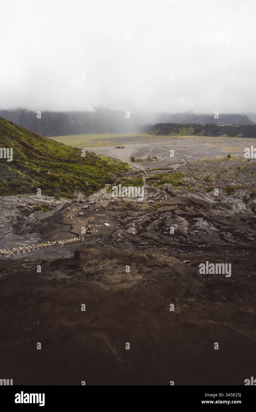 A mist-shrouded volcano rises in a vast natural landscape, Bromo ...