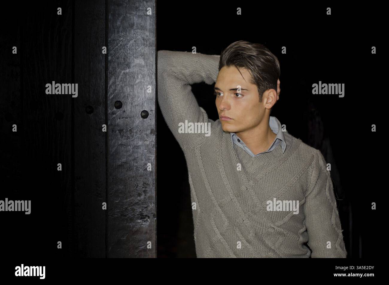 Handsome male model leaning on black wood door, large copy-space Stock ...