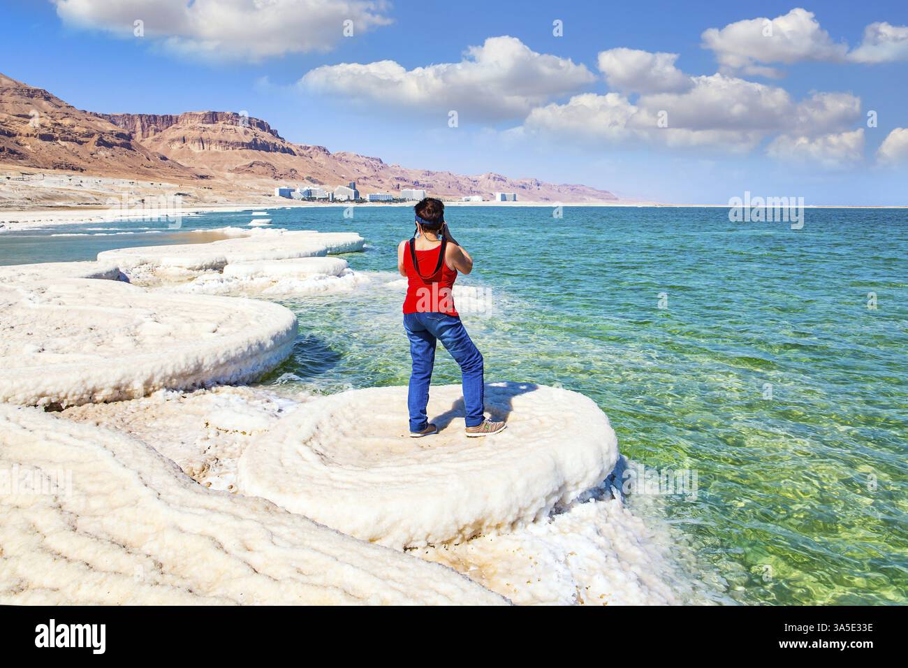 Woman in a red T-shirt photographs the sea surface. Evaporated salt ...