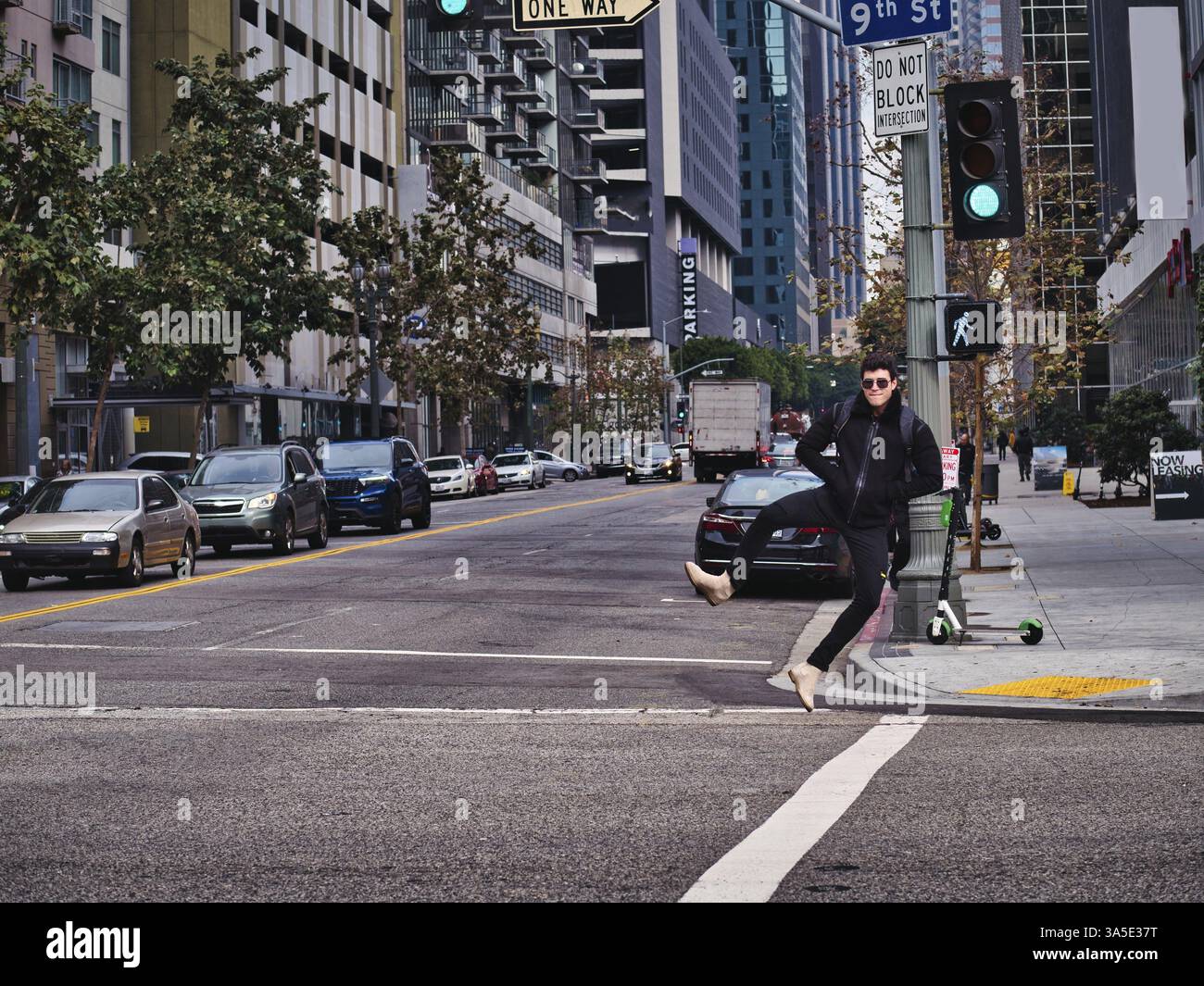 Full body young male with hands in pockets jumping happy while crossing ...