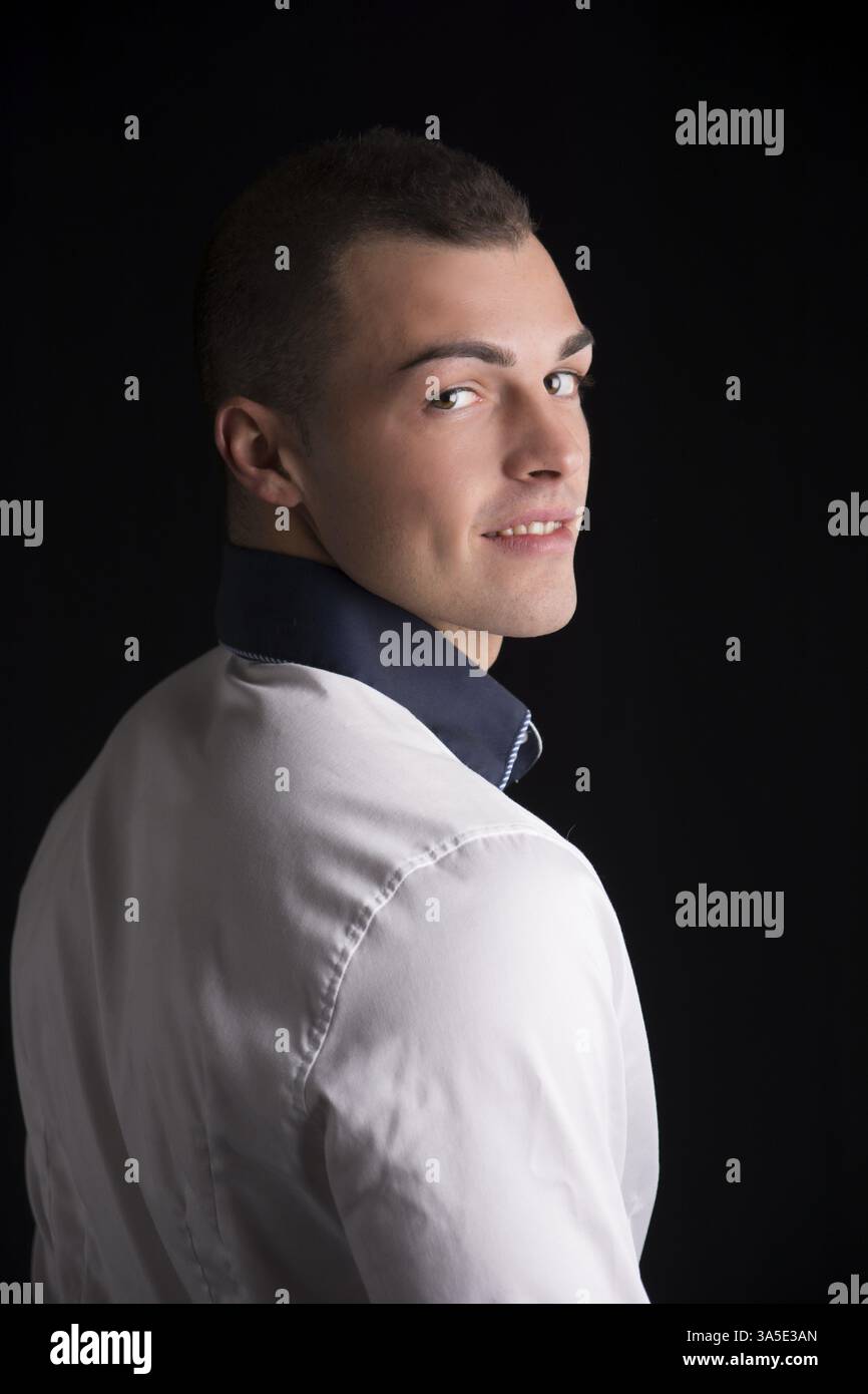 Attractive young man with white shirt, smiling to camera, turning ...
