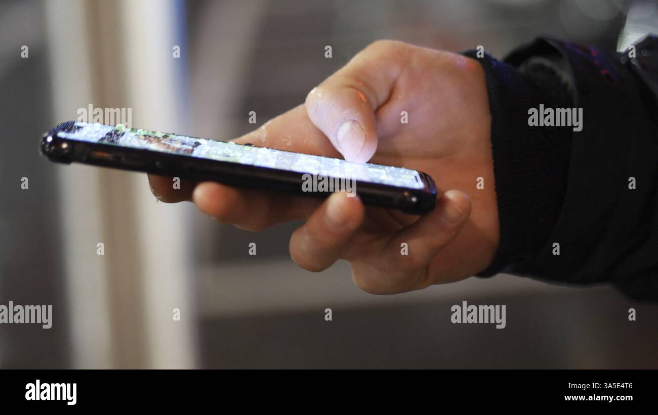 Male hands typing and using water-proof smartphone under rain dripping ...