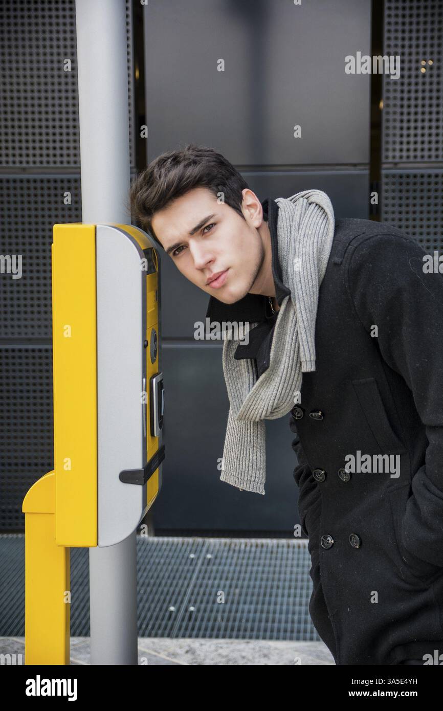 Handsome stylish young man bending down peering inside a glass entrance ...