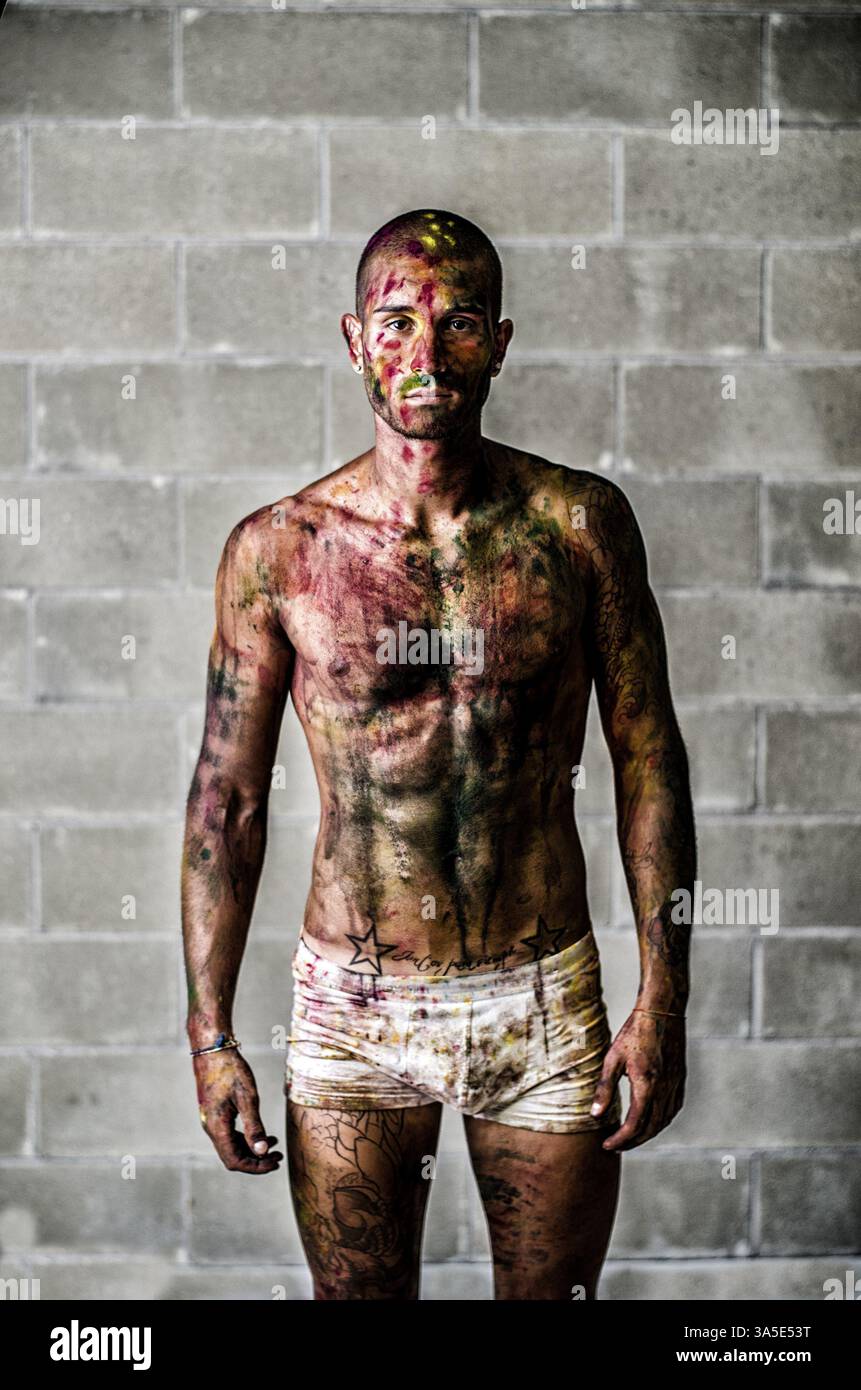 Handsome young man with skin painted all over with bright Holi colors ...