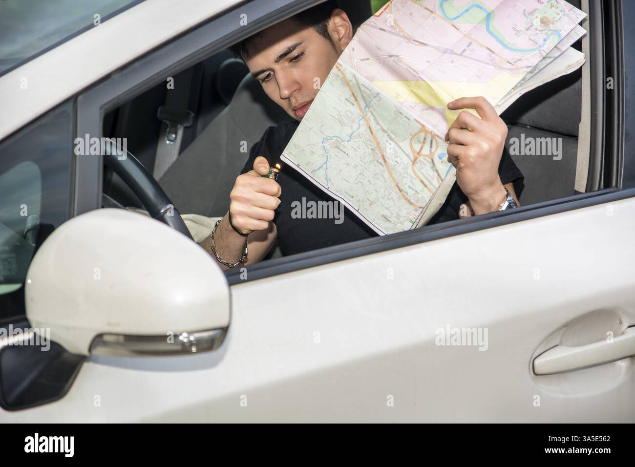 Handsome Young Man Burning a Map While Sitting Inside his Car with Open ...