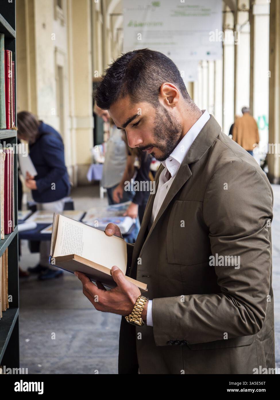 Side view of handsome man in elegant suit reading book in library Stock ...