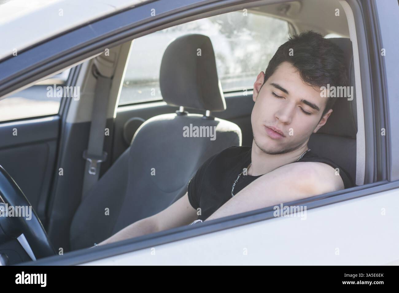 Handsome young man sleeping at the wheel driving his car. Danger ...