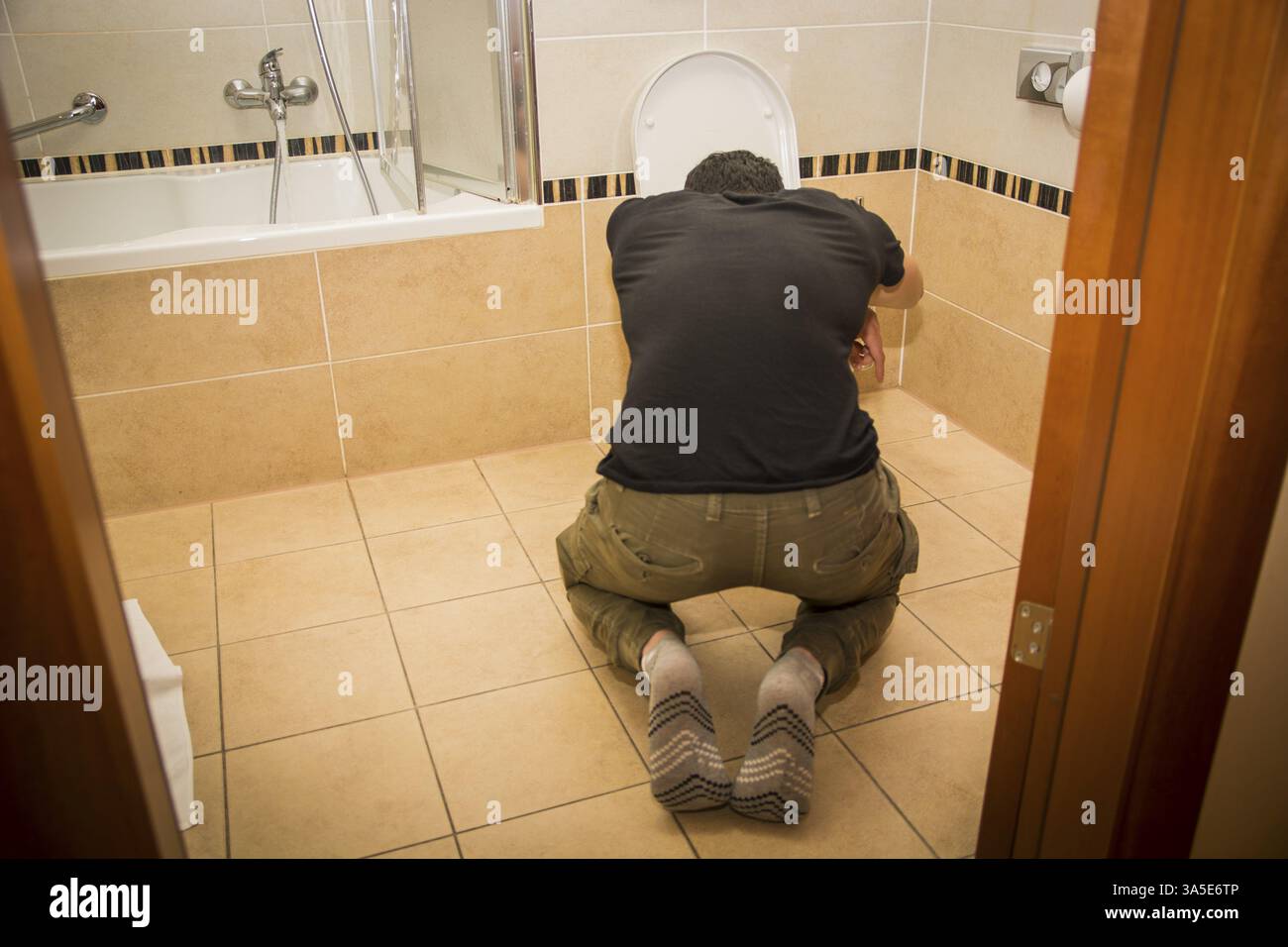 Rear View of a Drunk Young Man Vomiting in the Toilet at Home While in ...