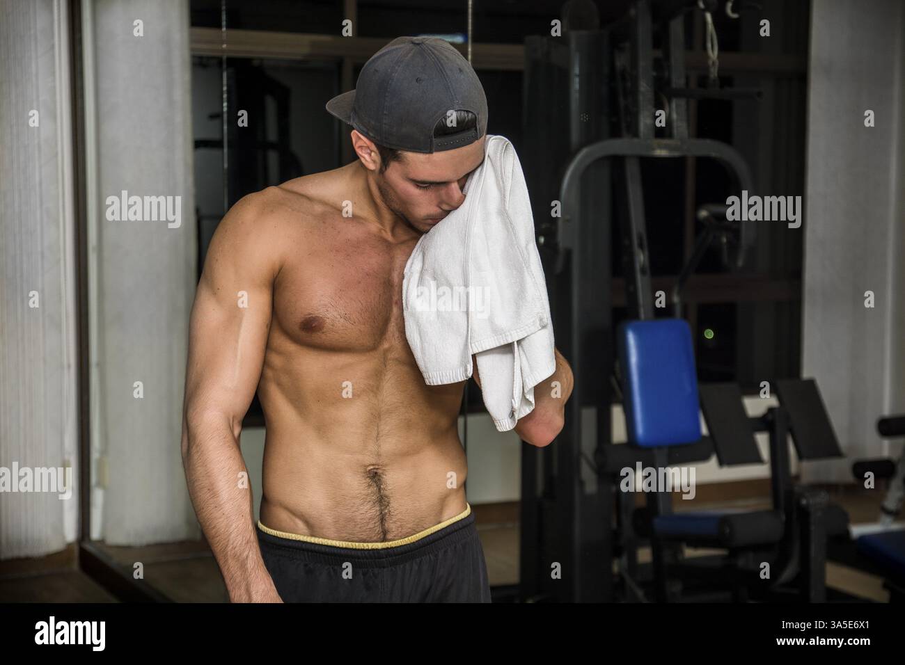 Muscular young man drying sweat from his face with a towel after ...