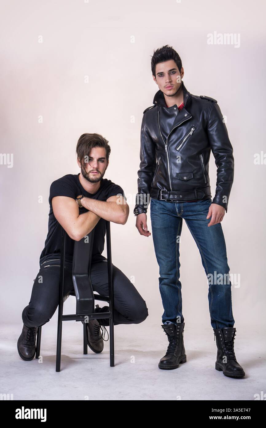 Two attractive young hard rock men posing in studio. Black background ...