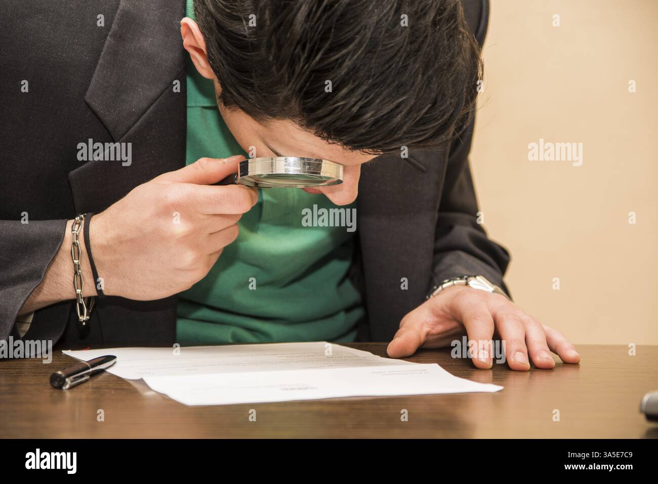 Young Man Sitting at Desk Scrutinizing Paper Contract with Magnifying ...