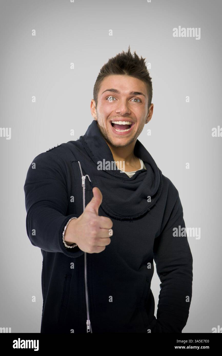 Attractive happy young man smiling, doing thumb up sign with his hand ...