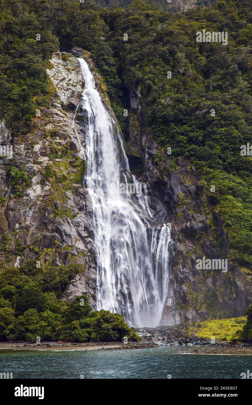 Magnificent powerful waterfall crashes down from the cliff of the fjord ...
