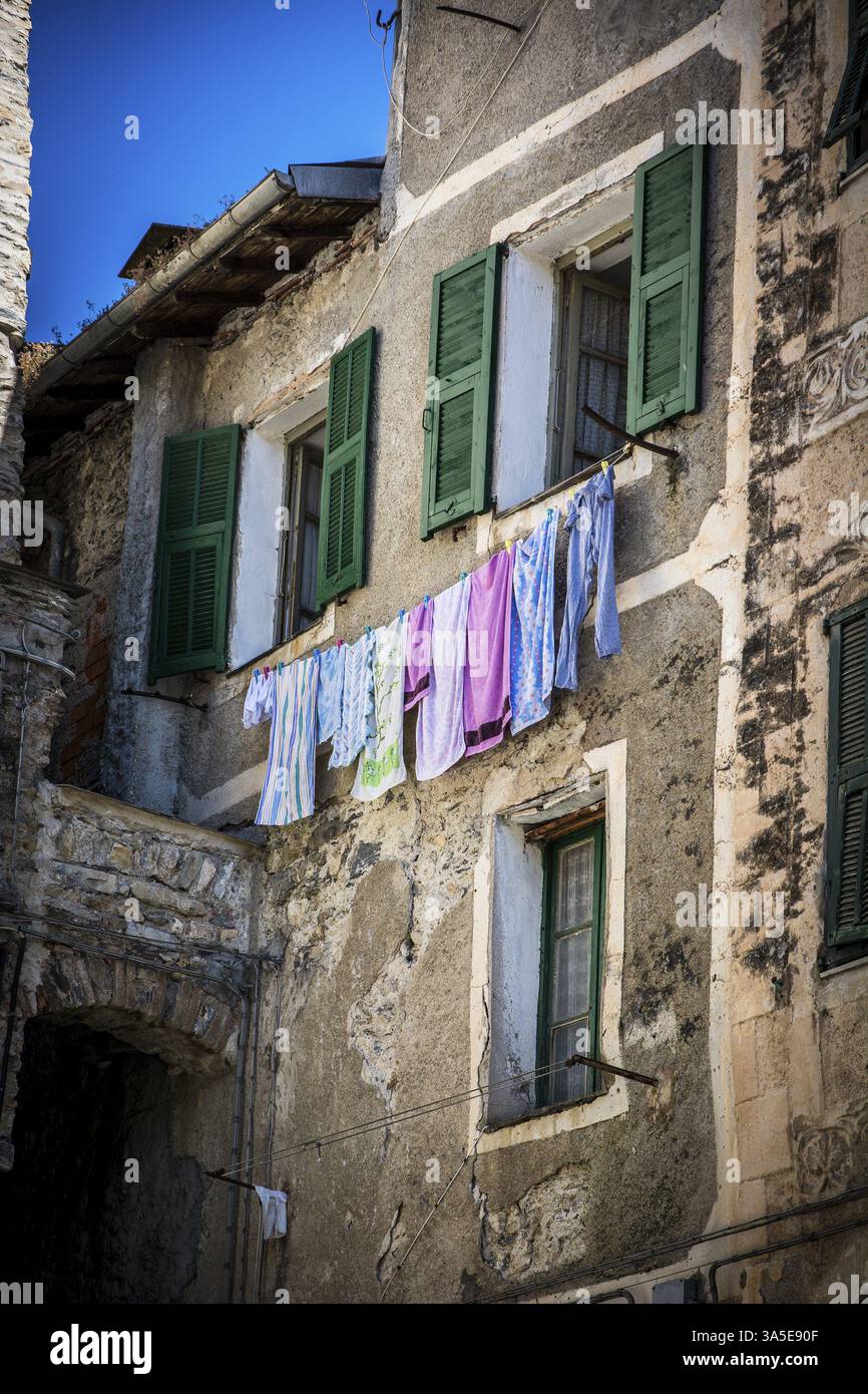 Old rough stone building with colorful windows and clothing on string ...