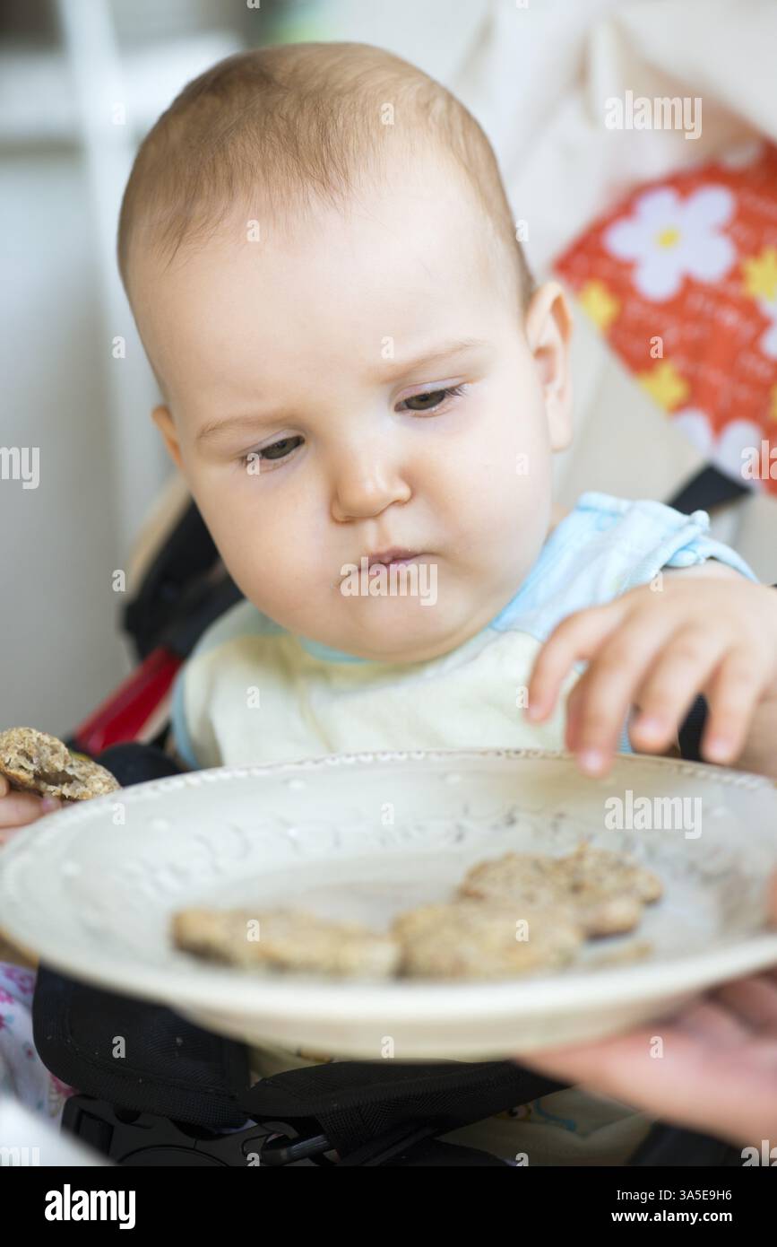 Baby eats alone. Eating homemade biscuits Stock Photo - Alamy