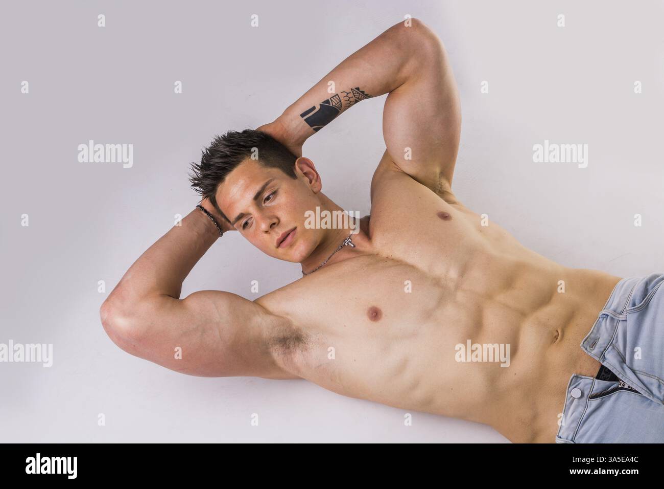 Handsome young bodybuilder laying down on the floor, showing ripped abs ...