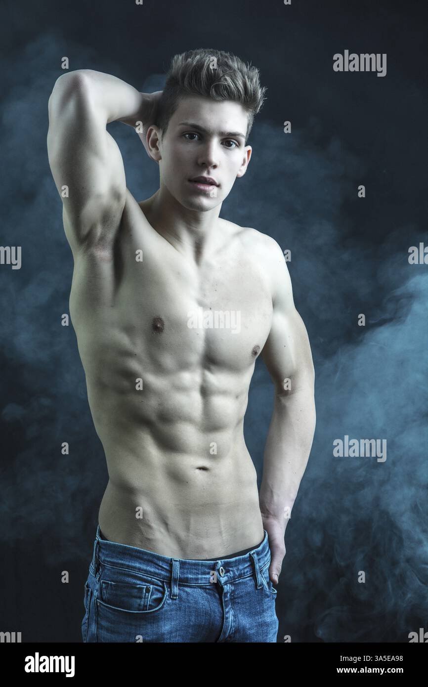 Handsome bodybuilder in relaxed pose, looking at camera on dark ...