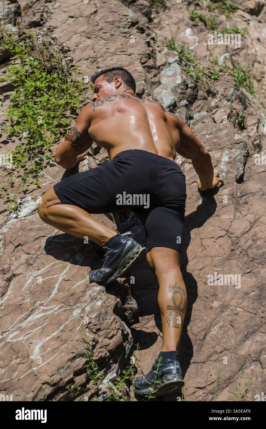 Handsome, muscular, shirless climber, looking in camera and climbing ...