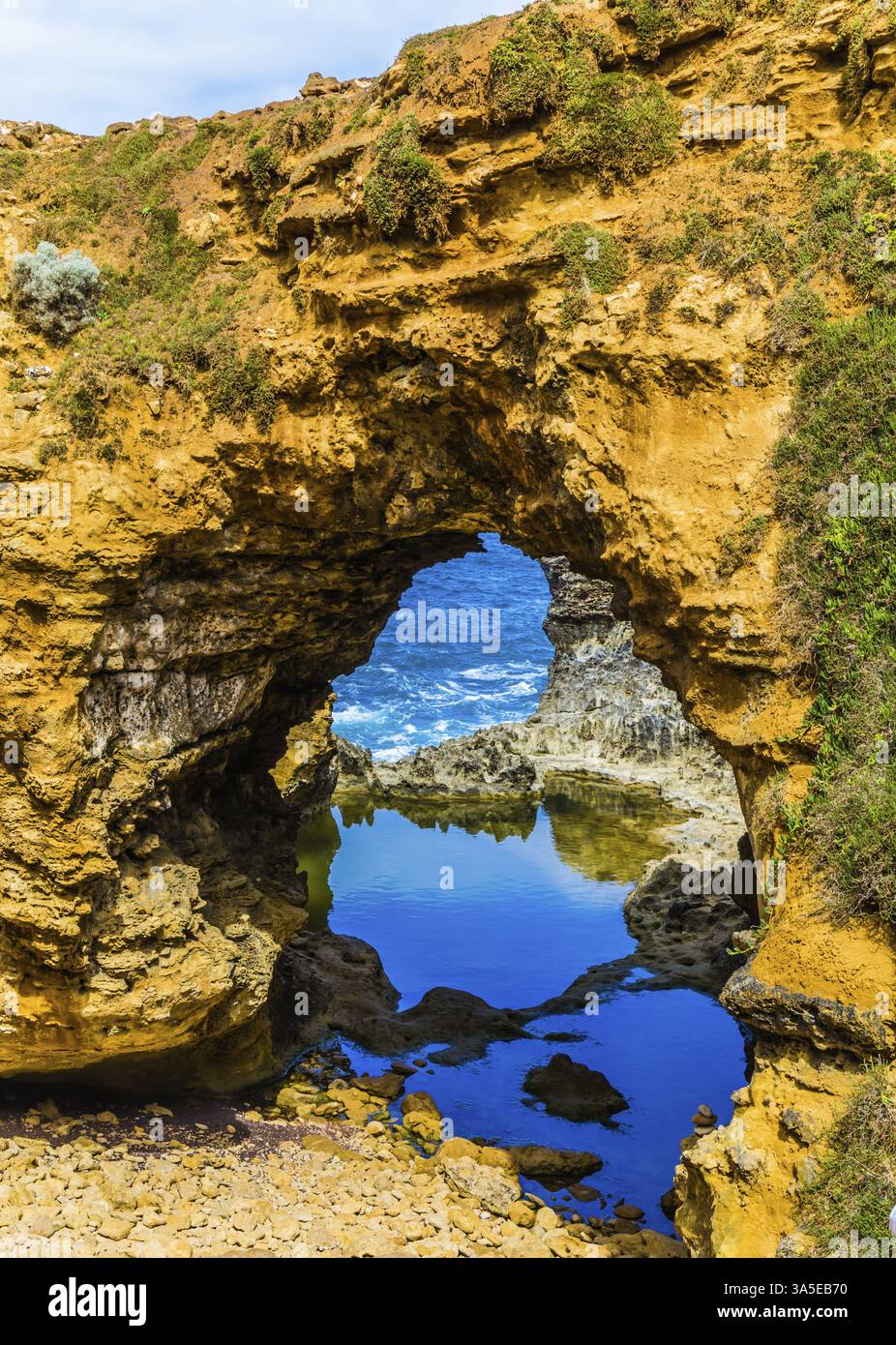 Coastal rocks formed a picturesque arch of sandstone. Puddle of quiet ...