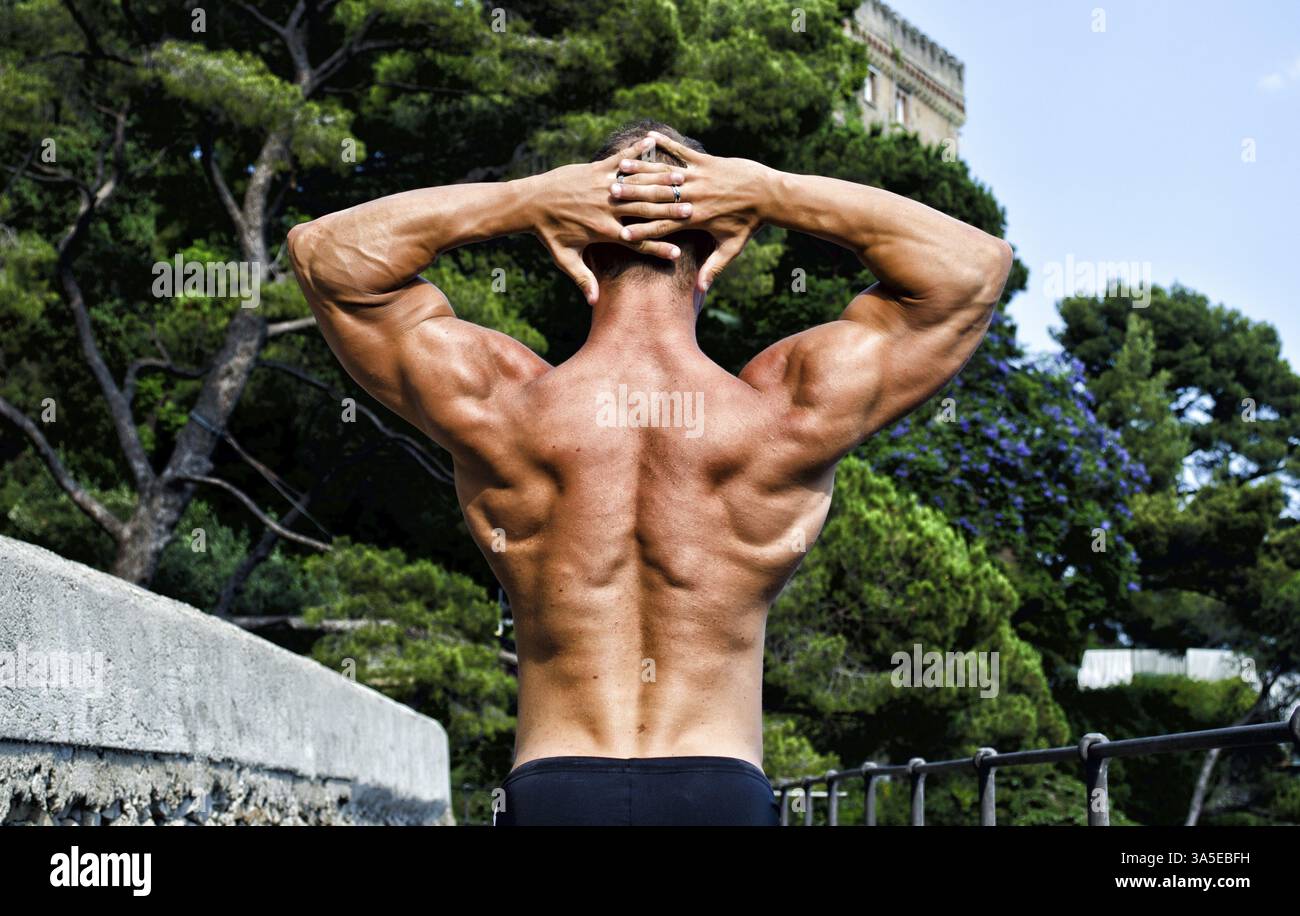 Muscular bodybuilder with hands behind his head showing back, shoulders ...