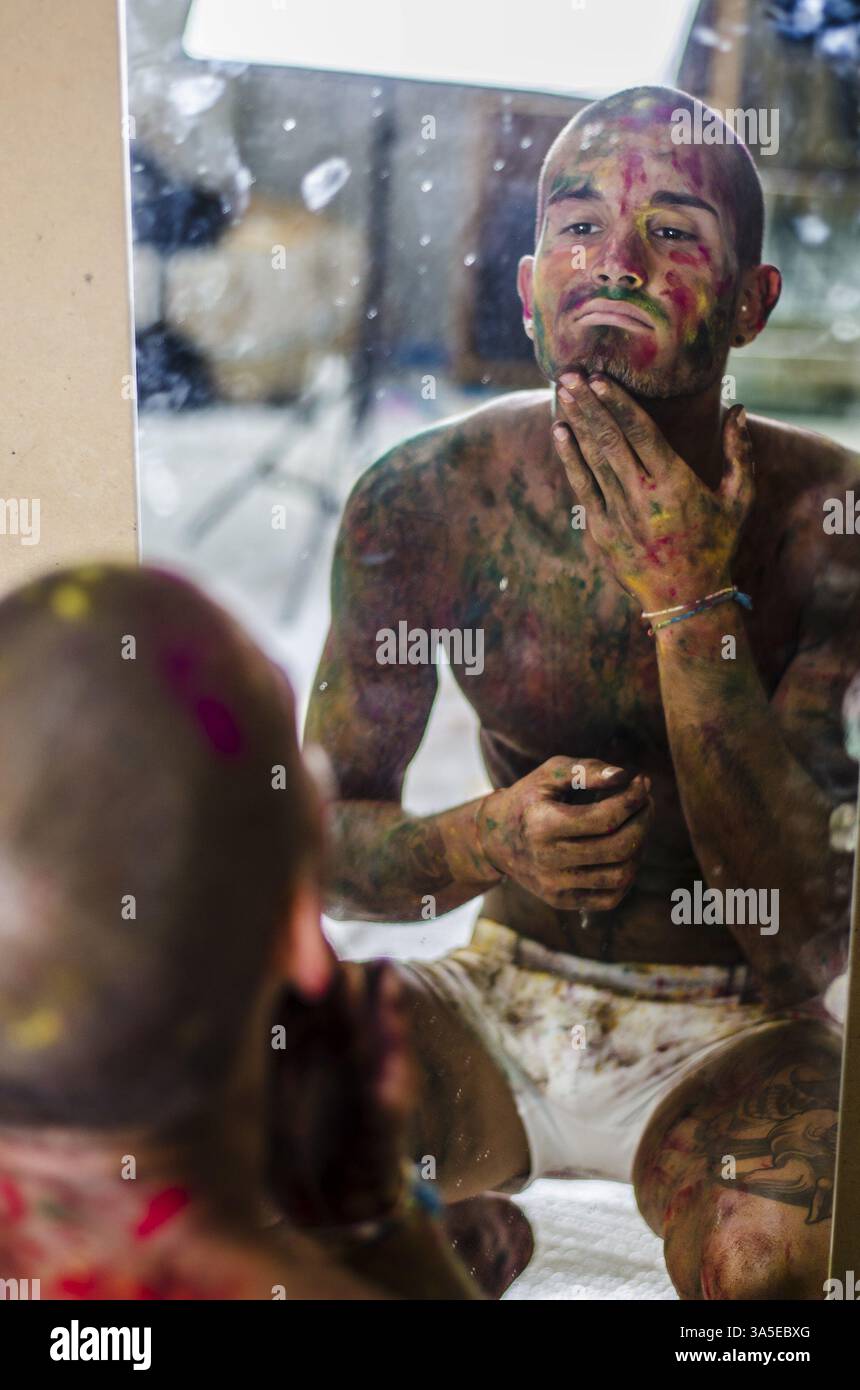 Side view of man with painted face applying holi color powders. Looking ...
