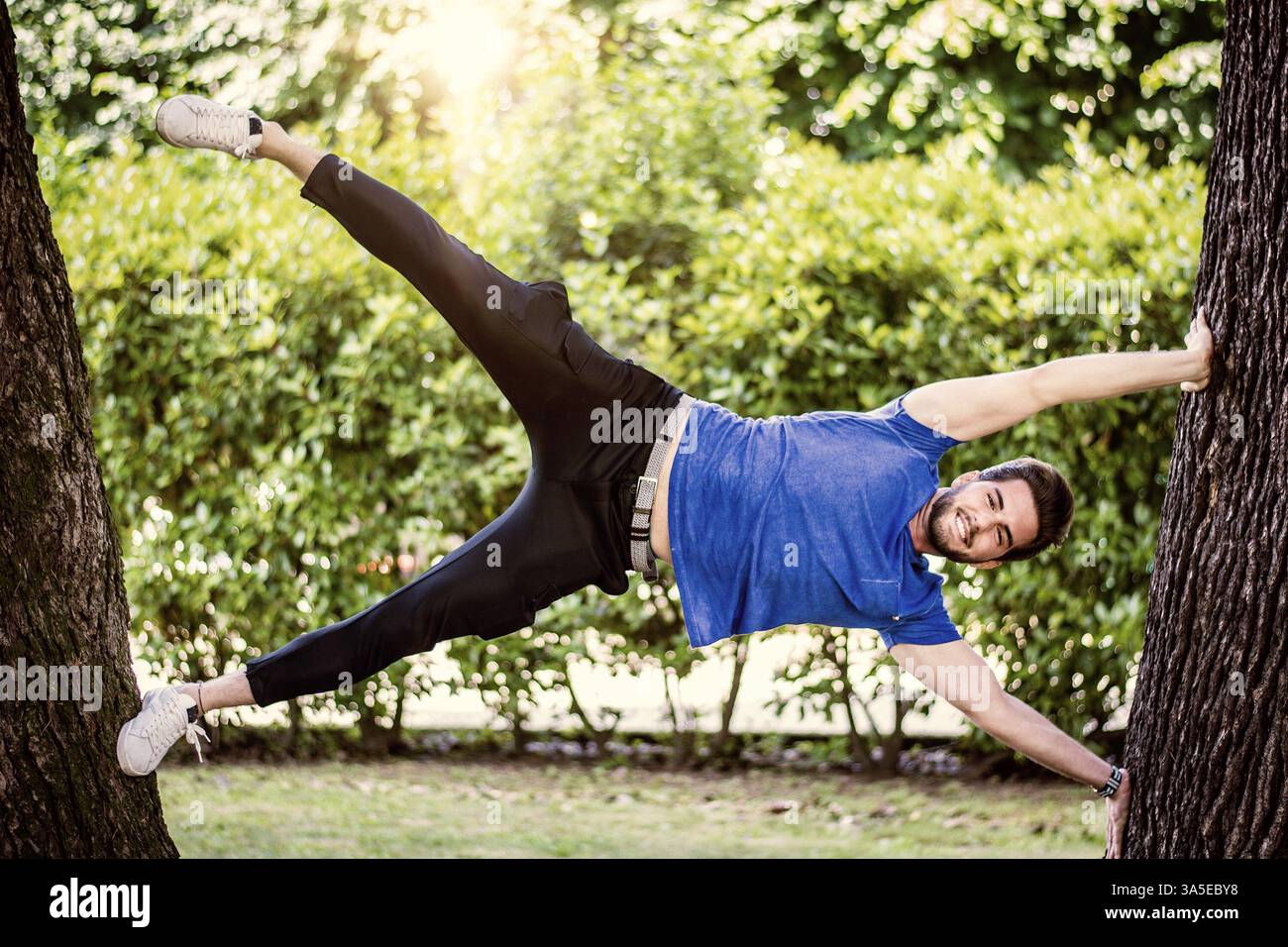 Cheerful fit man leaning with hands and legs on trunks showing plank ...