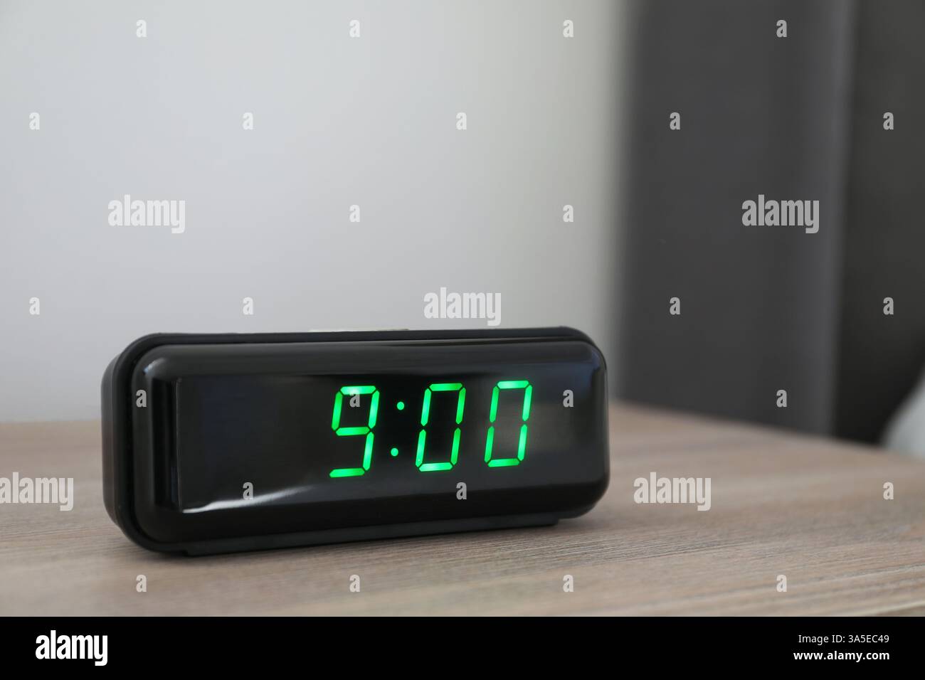 Digital alarm clock showing 9:00 o'clock on bedside table indoors Stock ...