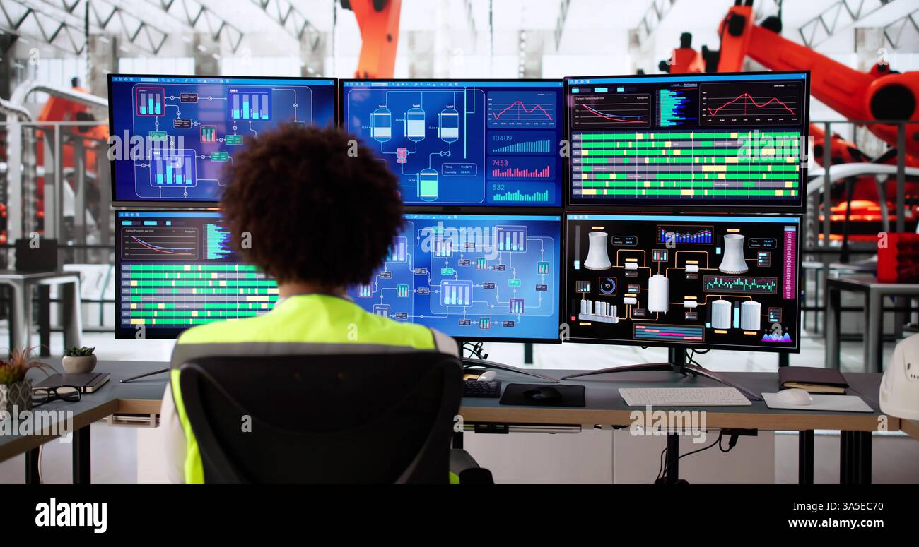 Young African American engineer operates Scada system at manufacturing ...