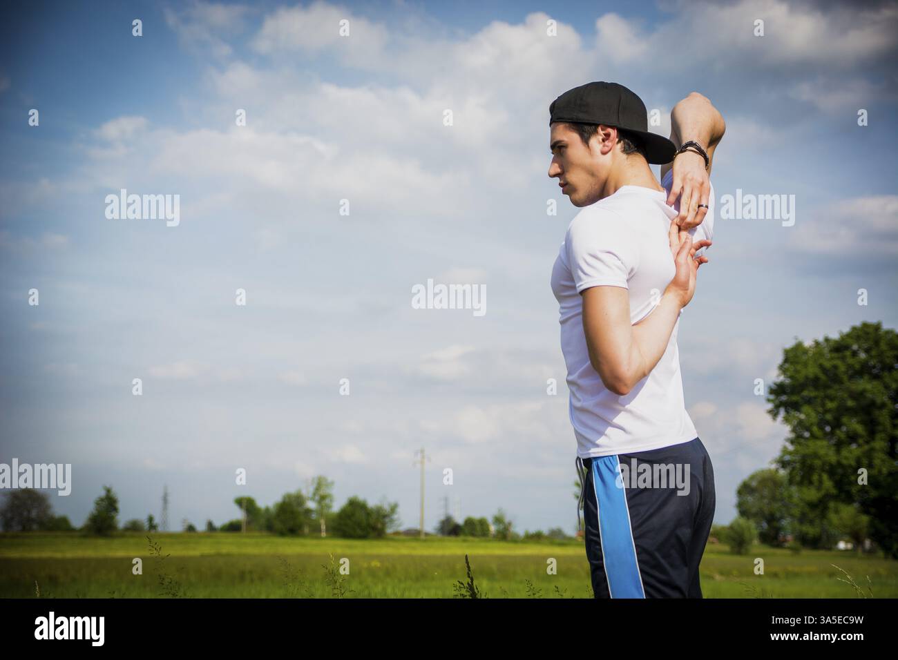Athletic, handsome fit young man outdoor in country doing stretching ...