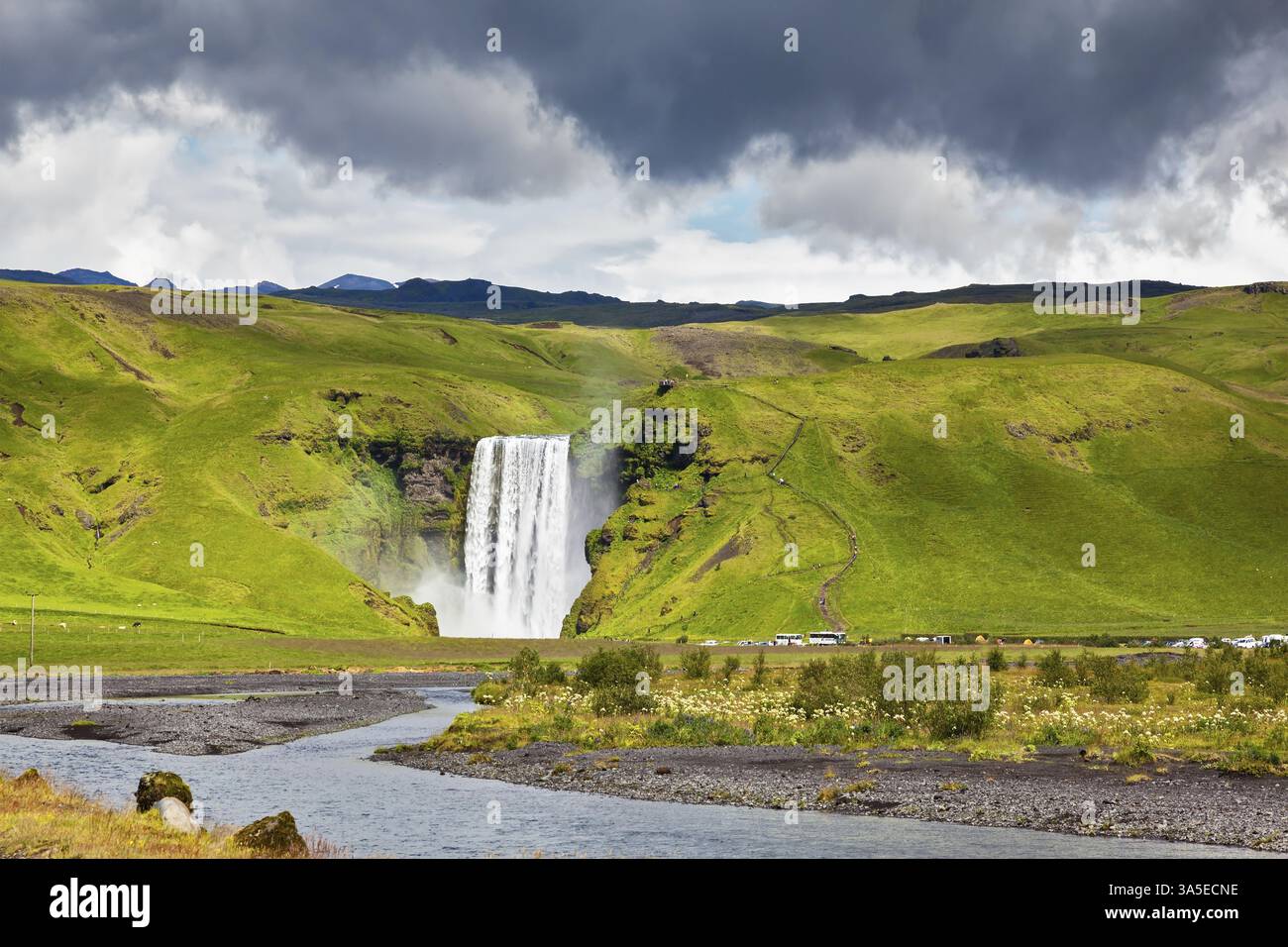 Huge picturesque waterfall and creek running along the road. Iceland ...