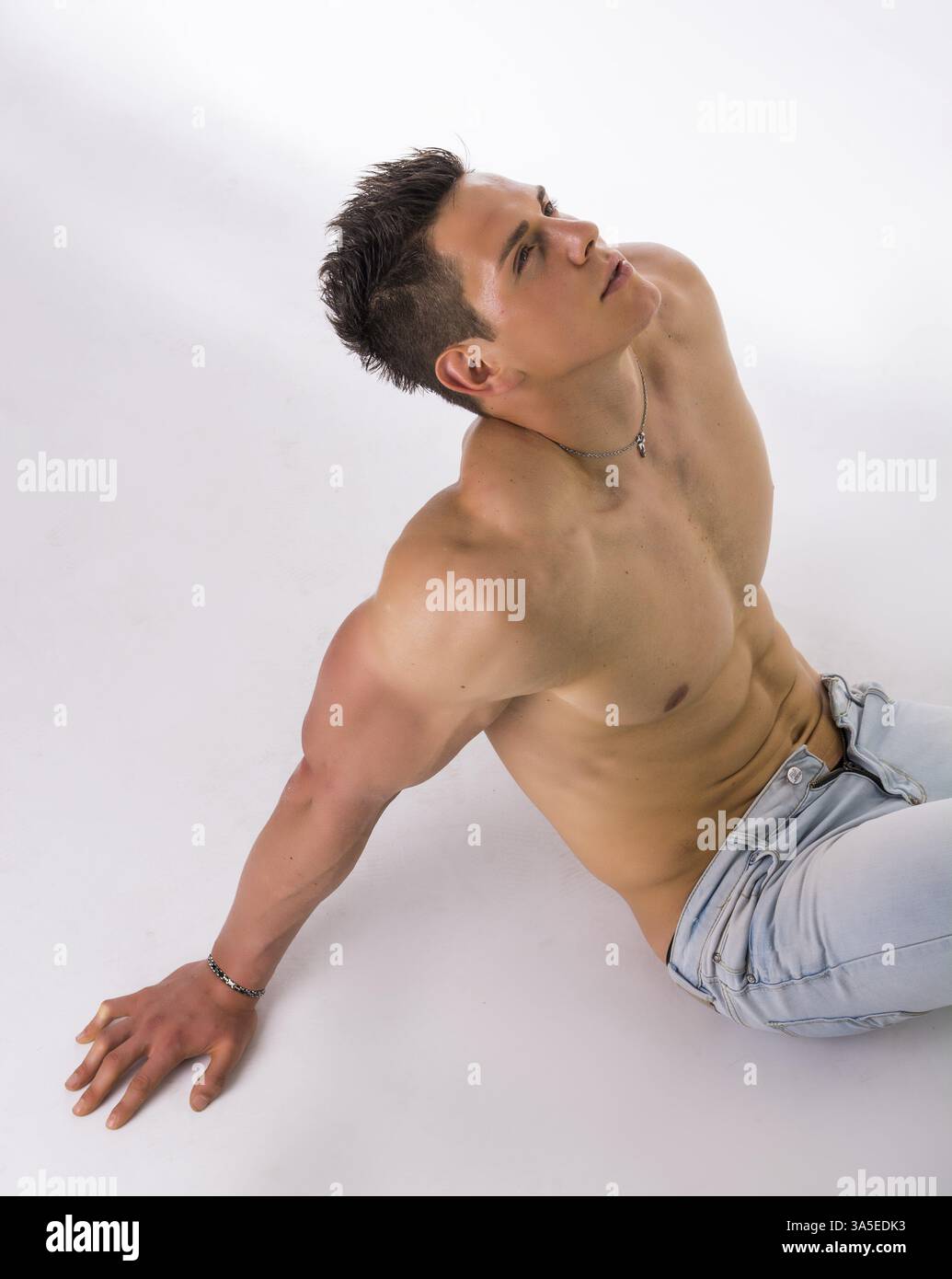 Handsome young bodybuilder laying down on the floor, showing ripped abs ...