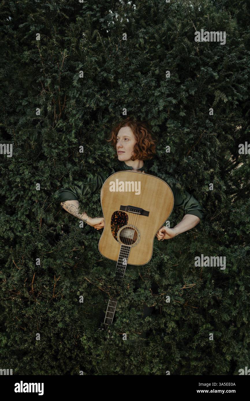 Red-haired guitarist with guitar in the green bush Stock Photo - Alamy