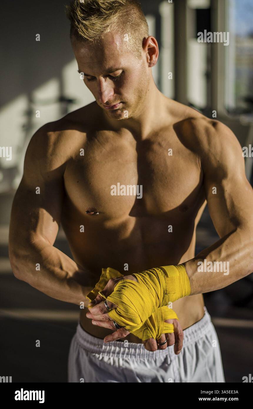 Muscular young man wrapping bandage around his hands for boxing Stock ...