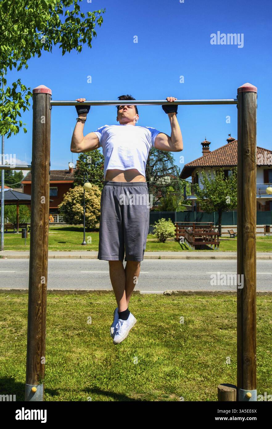 Attractive young man exercising and working out in outdoor gym in city ...